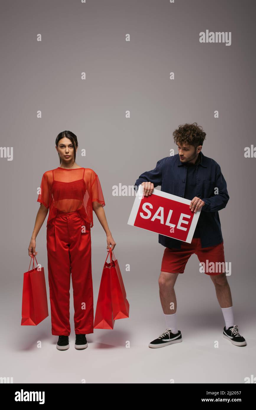 full length of young models in trendy outfits holding shopping bags and ...