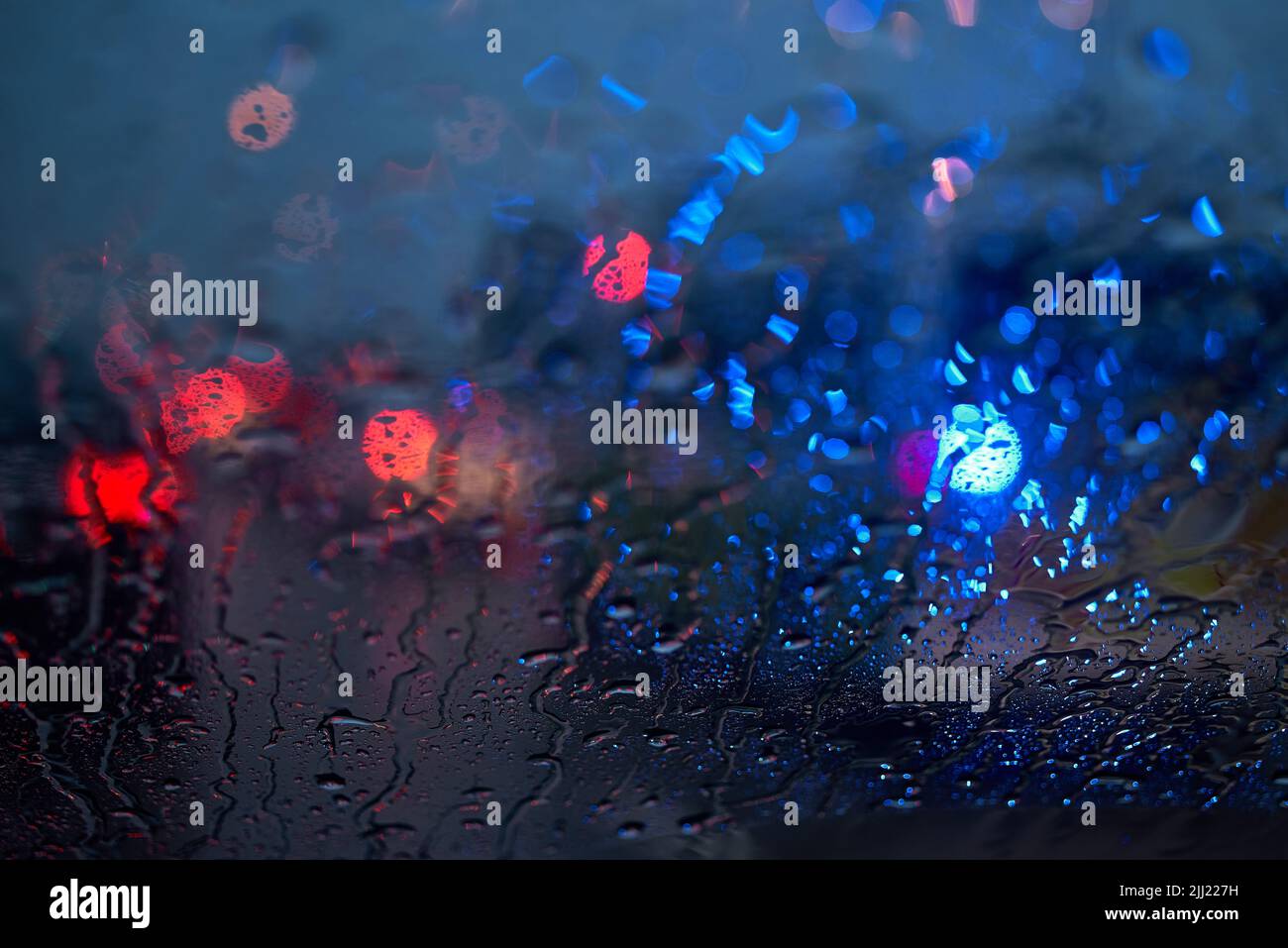 Light of the traffic and car on a rainy night through the windshield ...