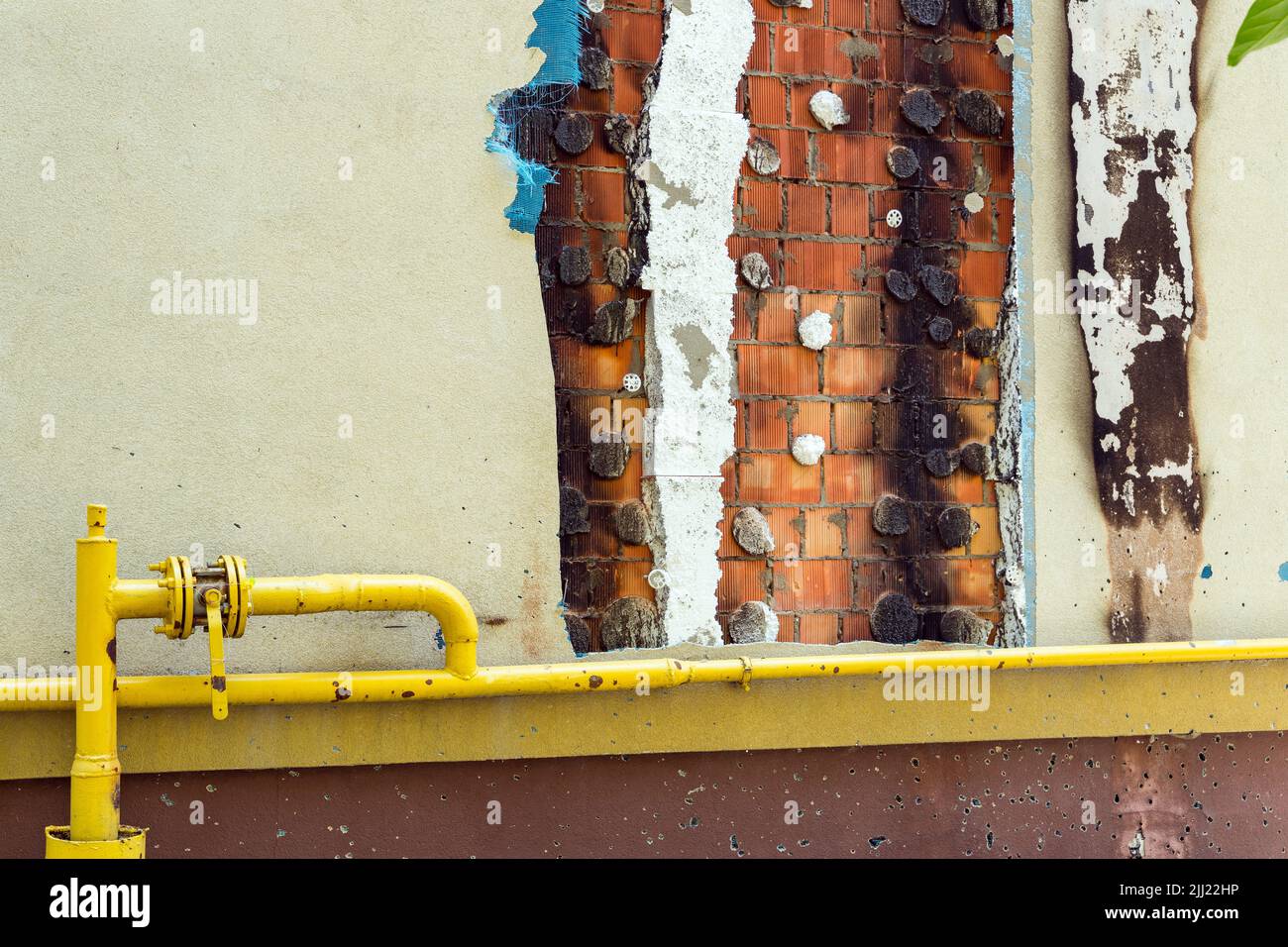 Closeup part of the building gas pipe damaged after shelling. A burnt ...