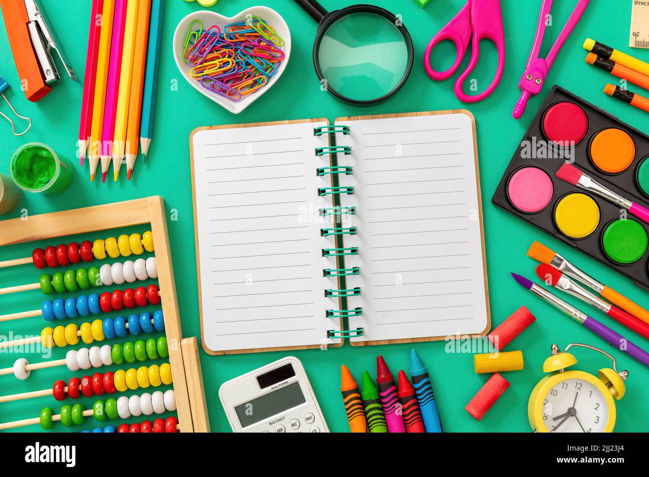 Back to school background. Open notebook on green color office supplies ...