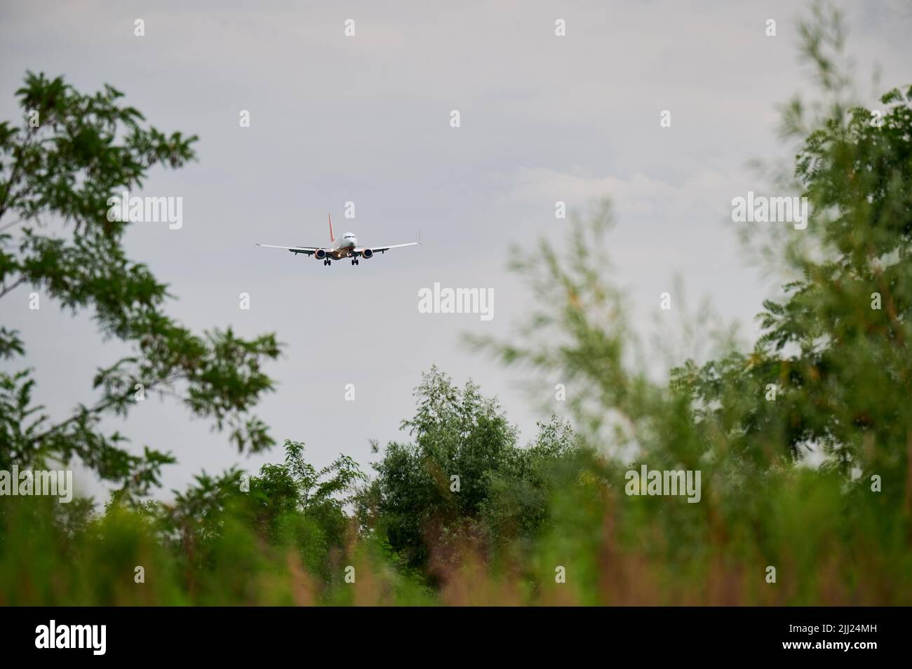 Commercial airplane flying in the sky. Front view of airliner landing ...