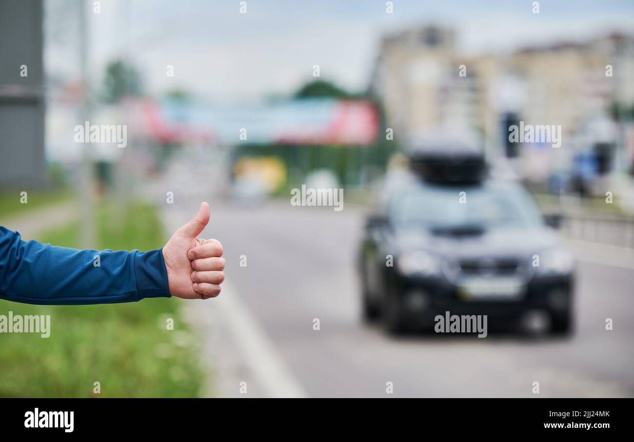 Close up of man's hand hitchhiking by roadside. Male hand showing ...