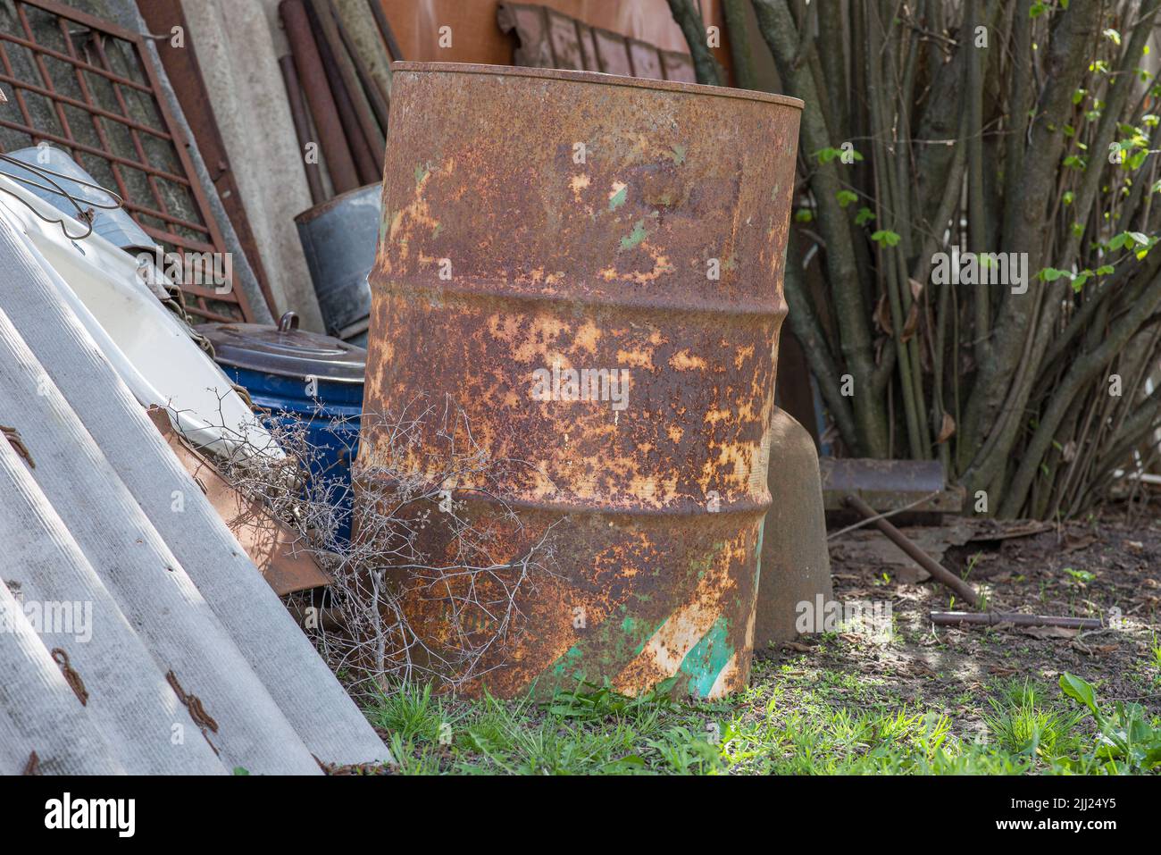An old rusty barrel stands next to a metal scrap. Metal barrel covered ...