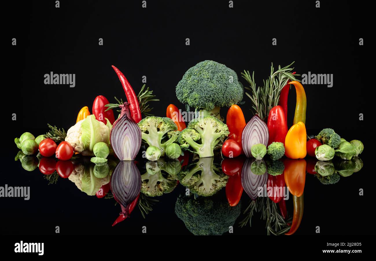 Various raw vegetables on a black reflective background. A conceptual ...