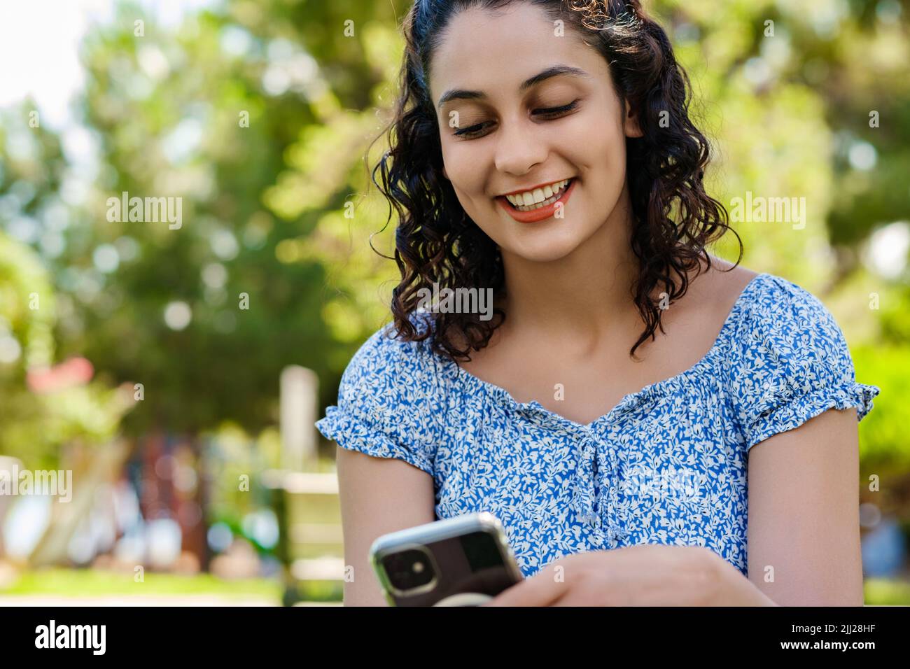 Cheerful brunette woman wearing summer dress on city park, outdoors ...