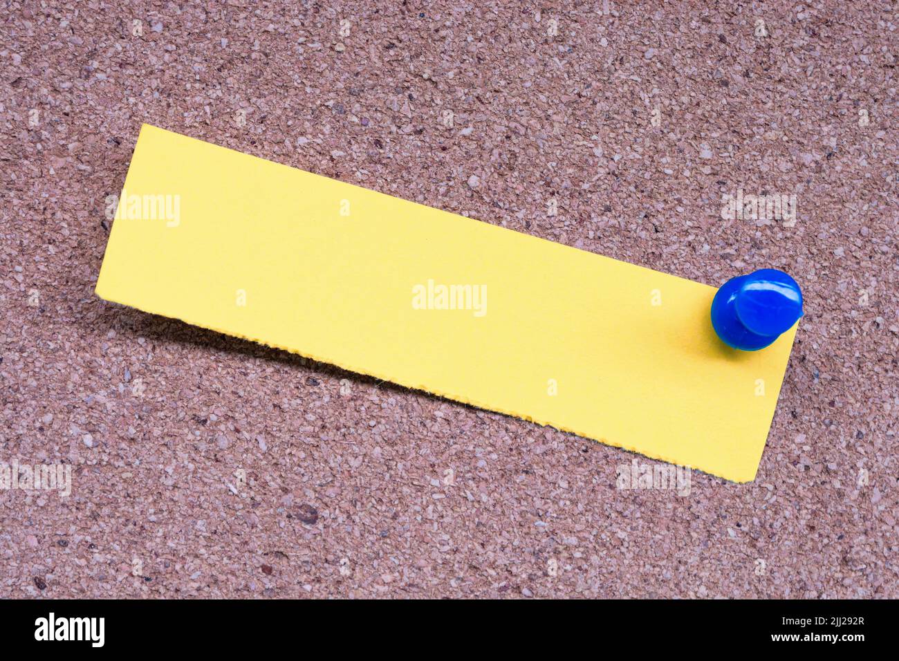 Yellow stick note and blue pinned to a cork notice board. Copy space ...