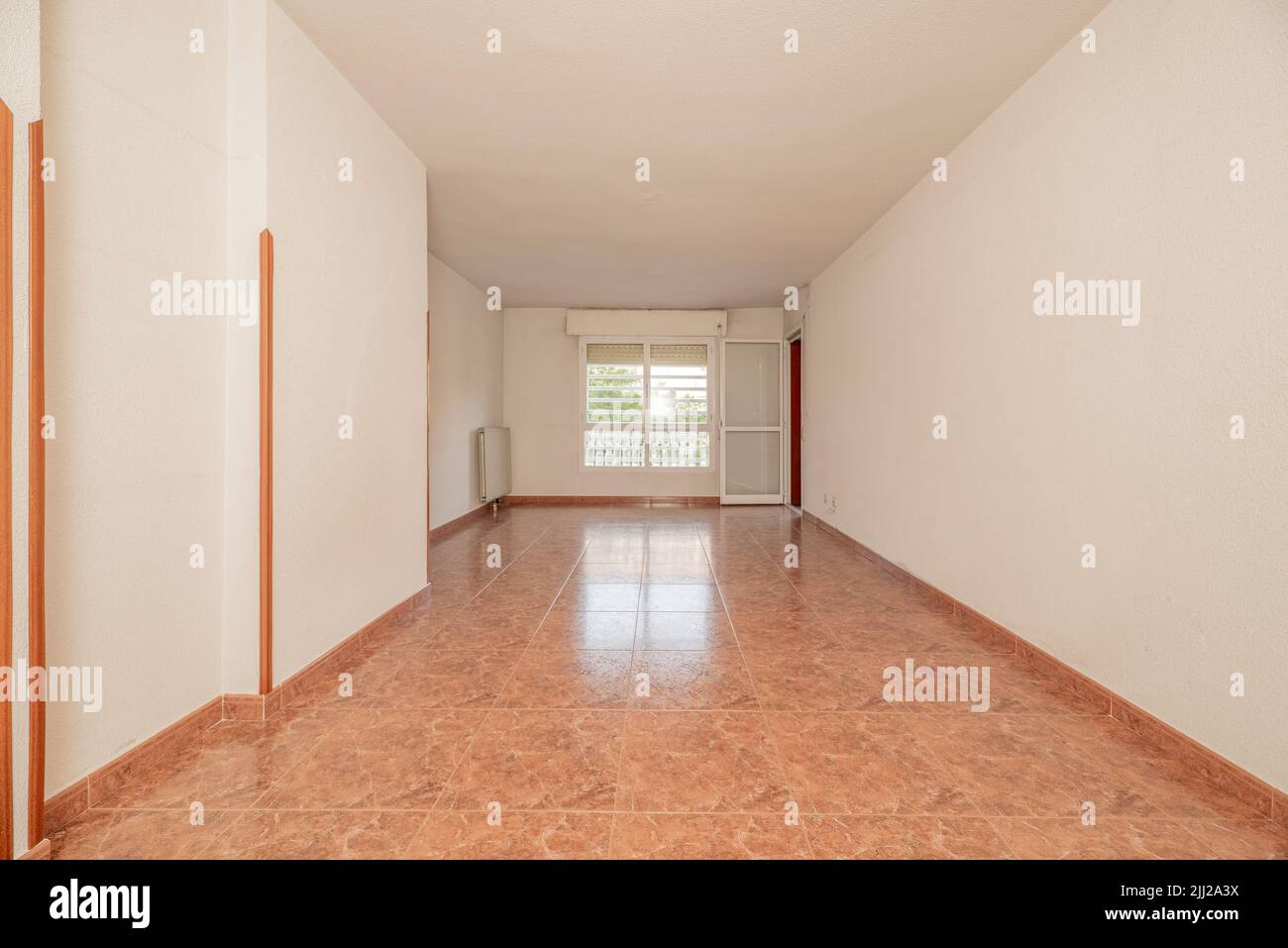 Empty room with a reddish stoneware floor, white painted walls and red ...