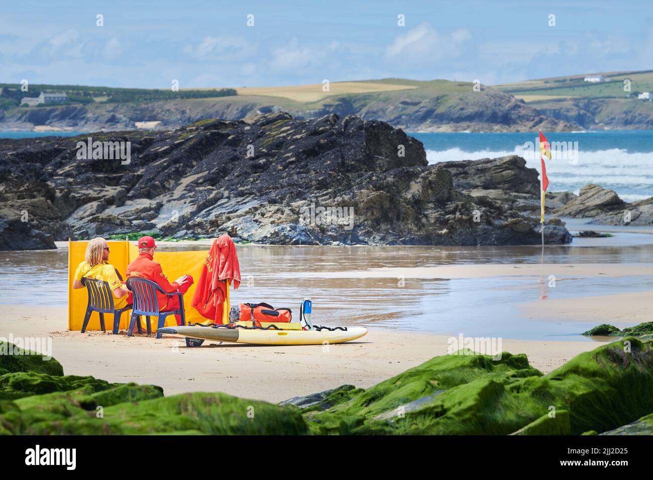 A couple of lifeguards sit behind their wind break on the sandy beach ...