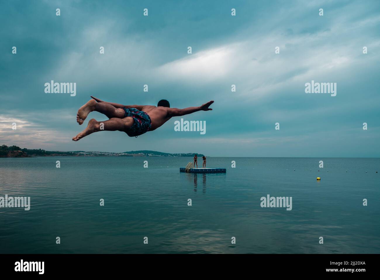 young person jumping into the sea from the pier Stock Photo - Alamy