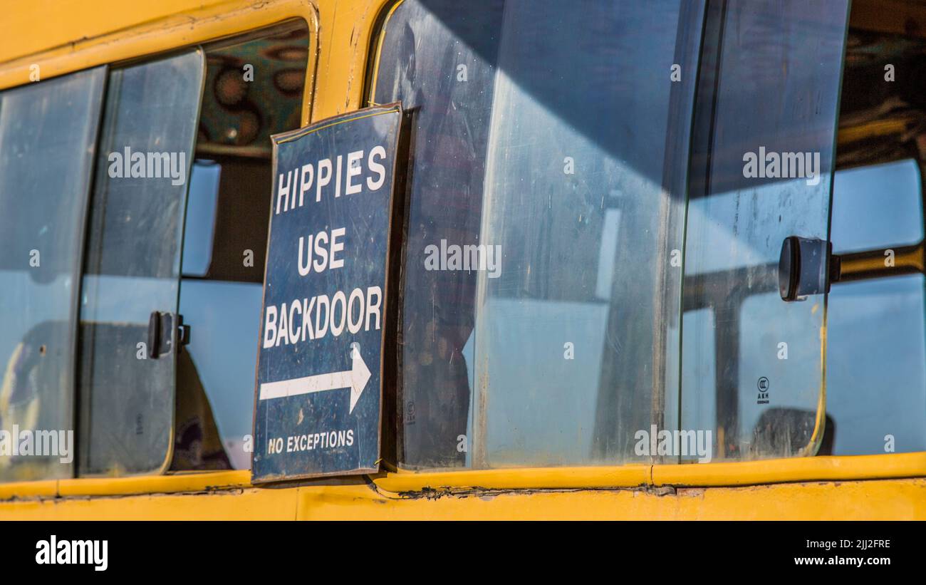 A closeup of a sign about hippies entrance on an old yellow bus window ...