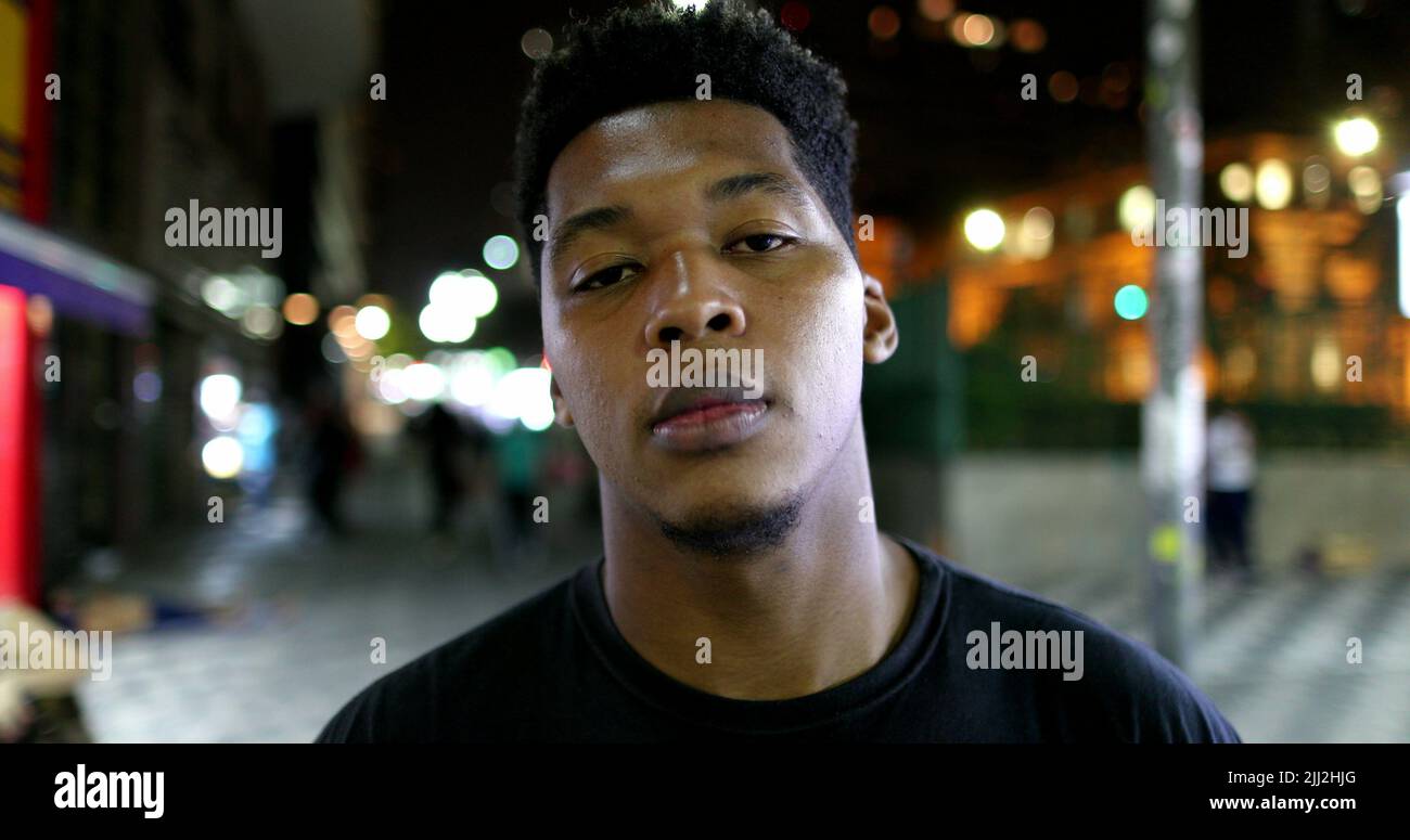 African male standing outside in city looking at camera with serious ...