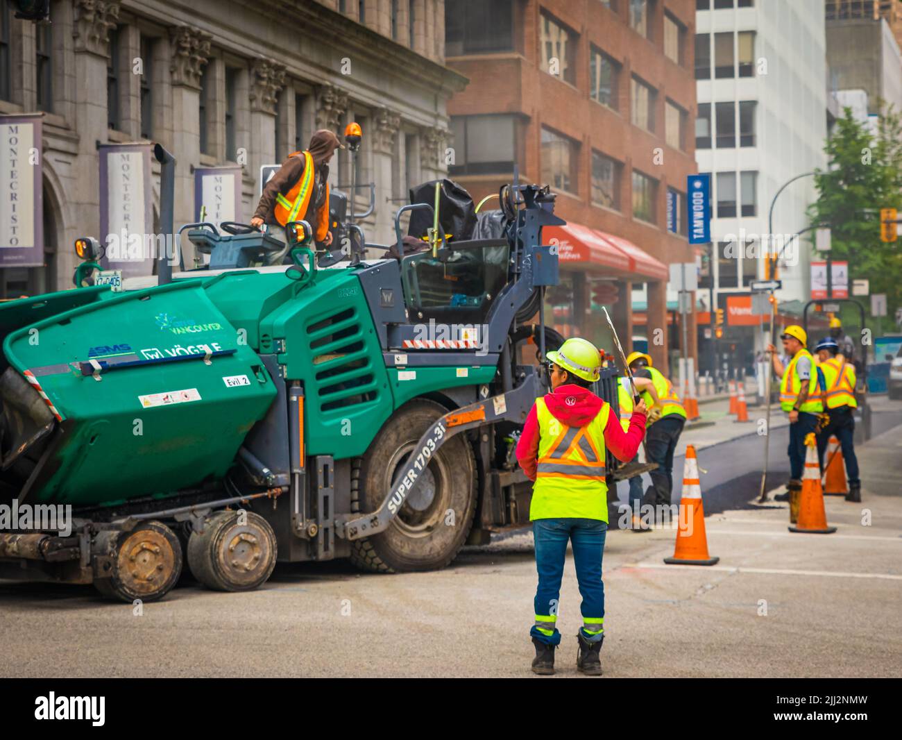 Team of workers put the hot asphalt on a road. Road construction ...