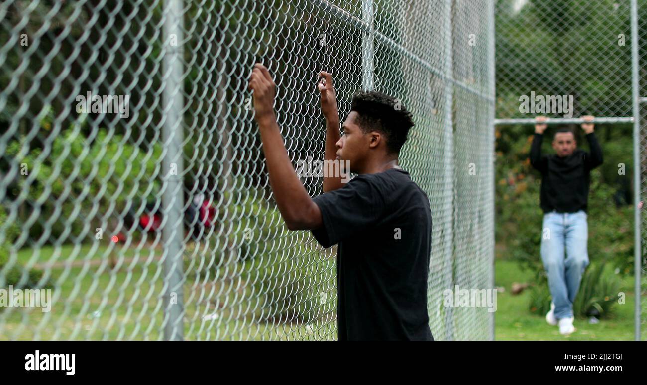 Pensive young black man leaning on metal fence. Contemplative mixed ... Pensive young black man leaning on metal fence. Contemplative mixed ...