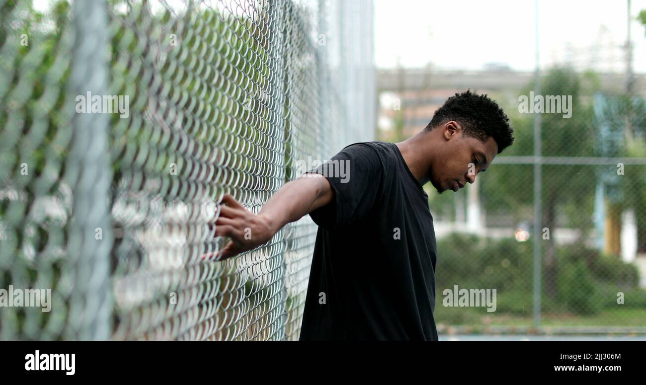 Black guy at basketball court holding into metal fence posing Stock ...