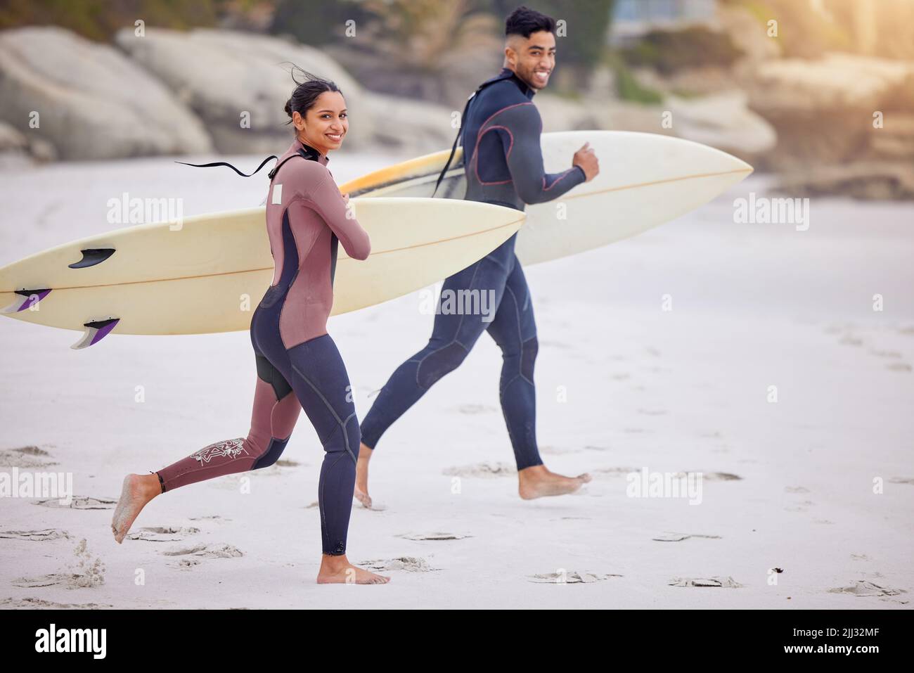 Surfing is almost a way to fly. Portrait of a young couple running ...