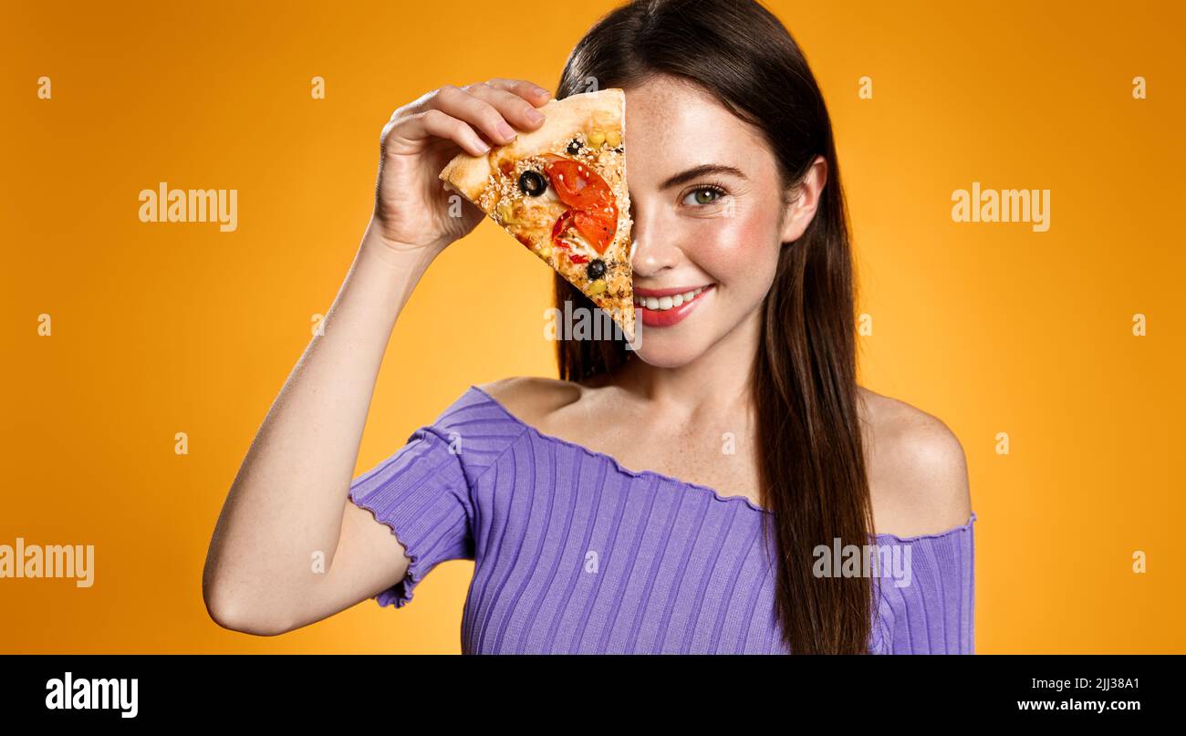 Beautiful girl showing slice of pizza near her face and smiling ...