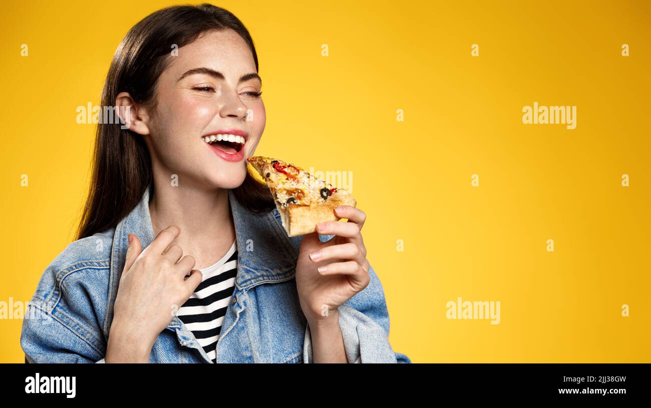 Image of girl smiling while biting slice of pizza, happy face at ...