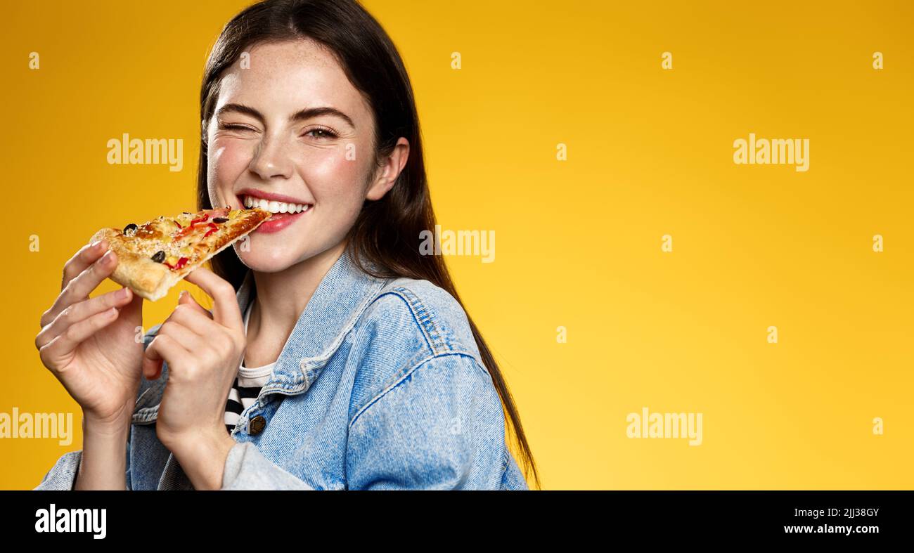 Pizza and delivery concept. Happy woman posing with pizza slice, eating ...