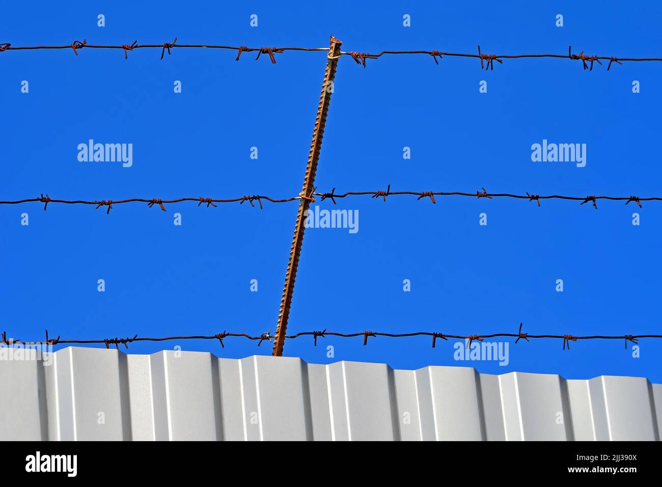 vintage metal grid with barbed wire on blue sky in sunny day ...