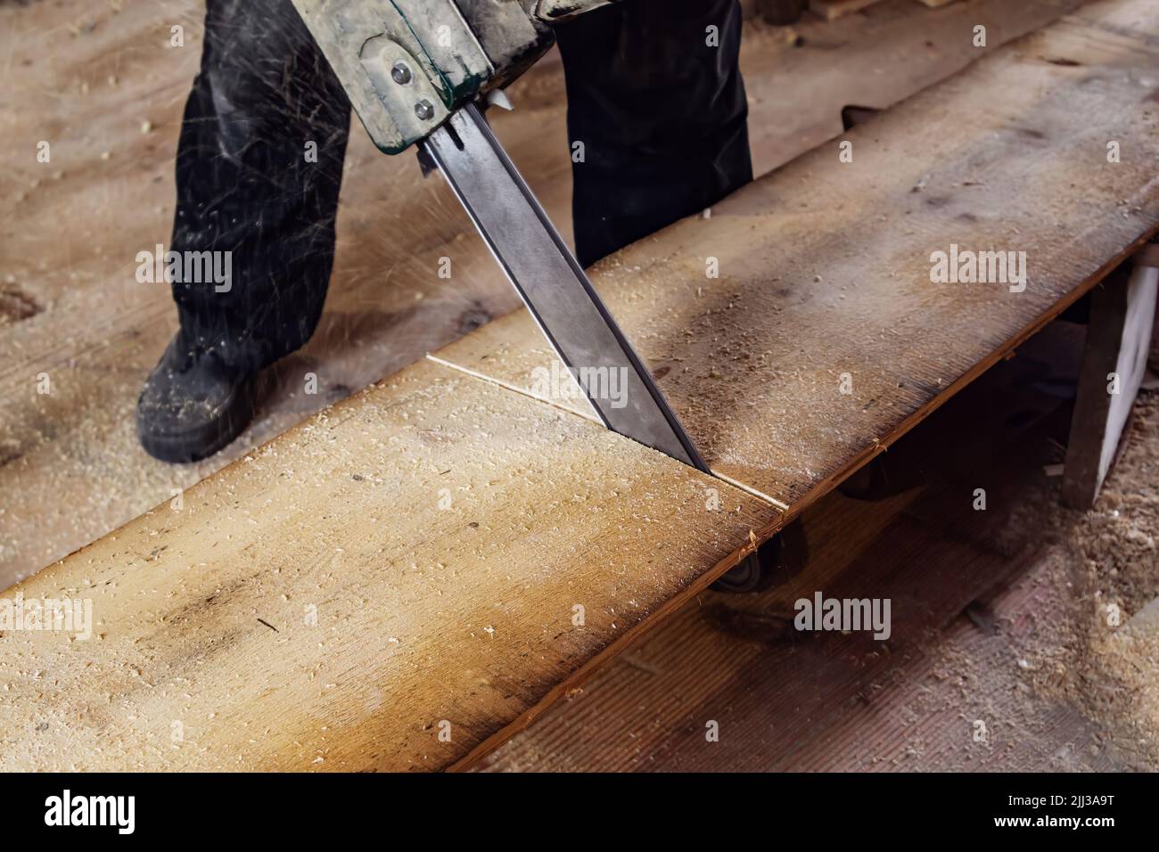 carpenter is sawing a wooden board with an electric saw. Flying ...