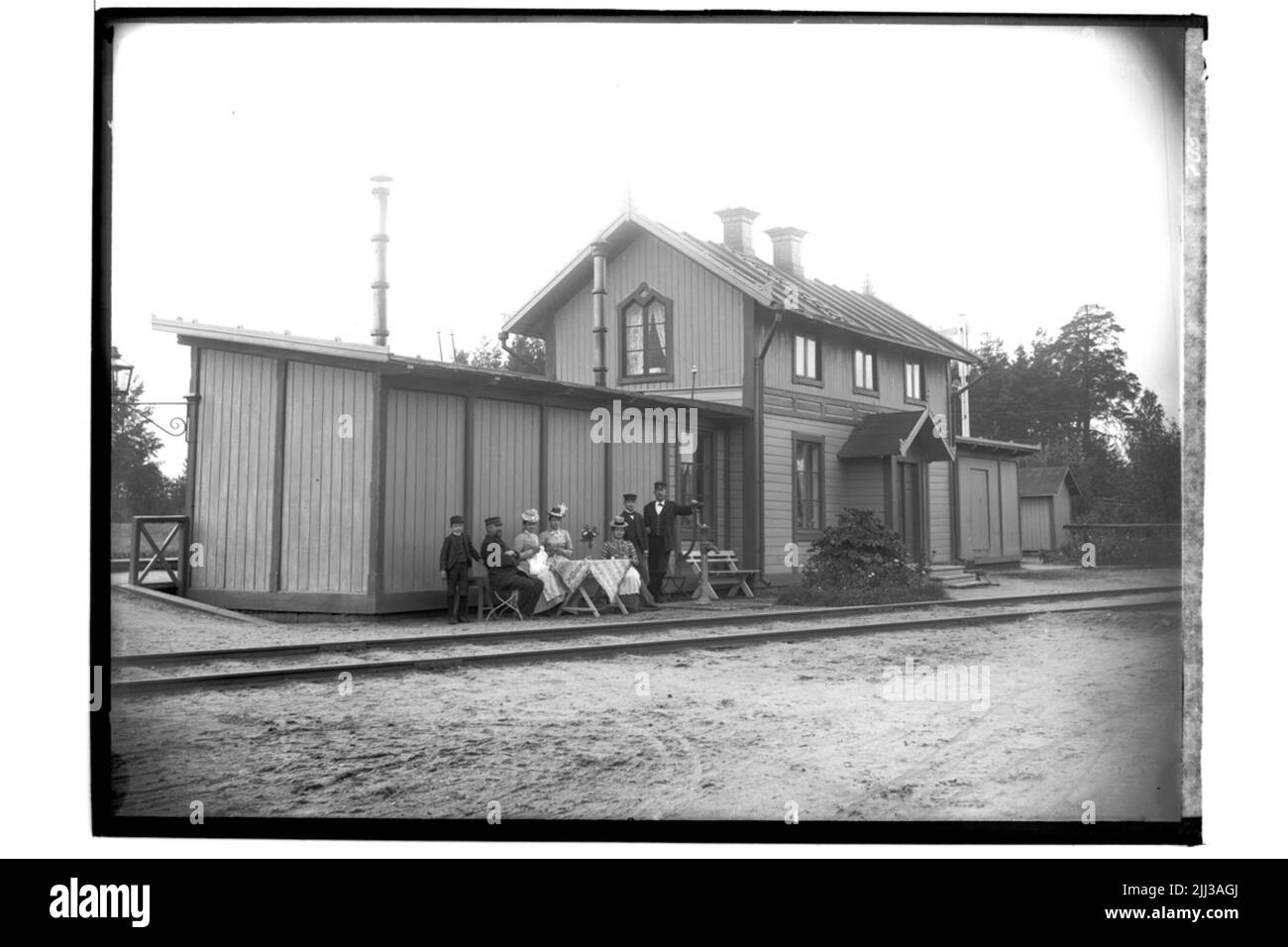 Two -storey station building with two wings. 7 people at the back of ...