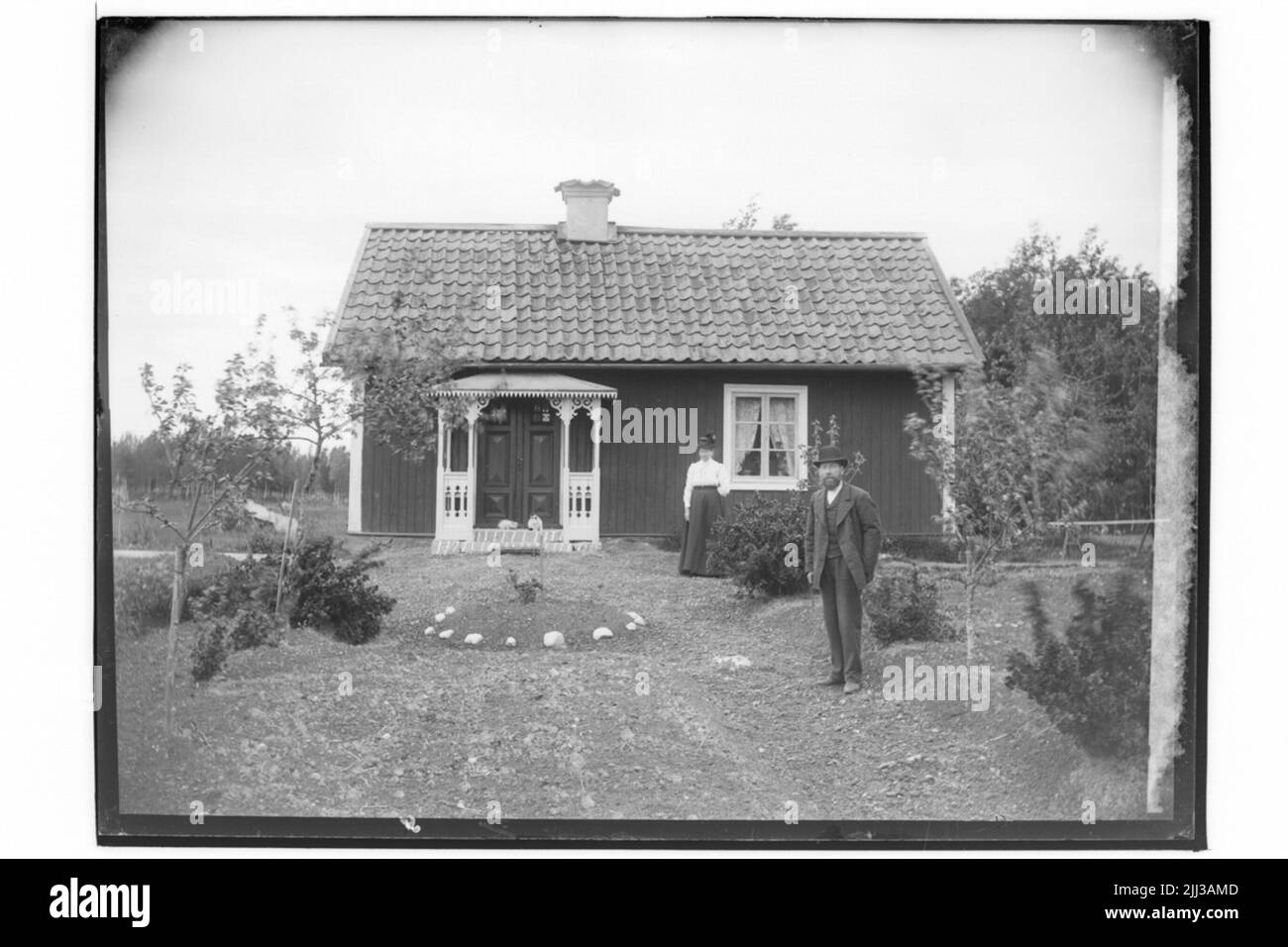 One -storey residential building, single cottage. 2 people in front of ...