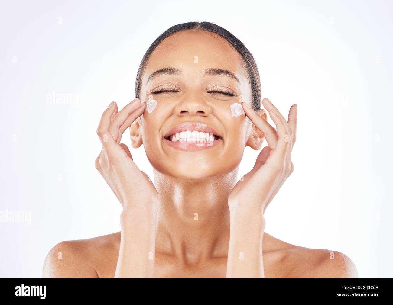 Happiness shines from the inside. a young woman applying moisturiser to ...