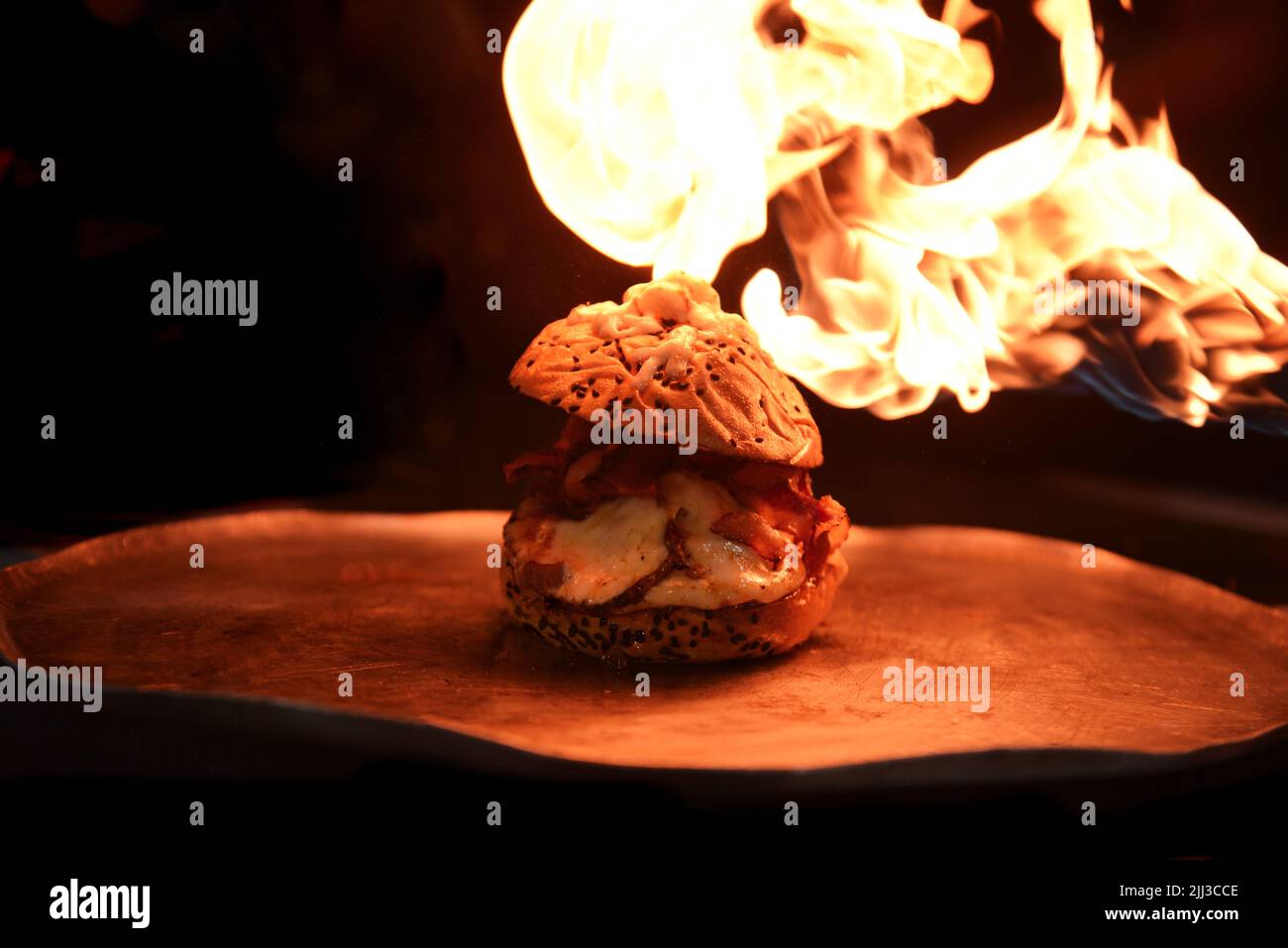 Burger and hot dog cooked on fire during preparation with flamethrower ...