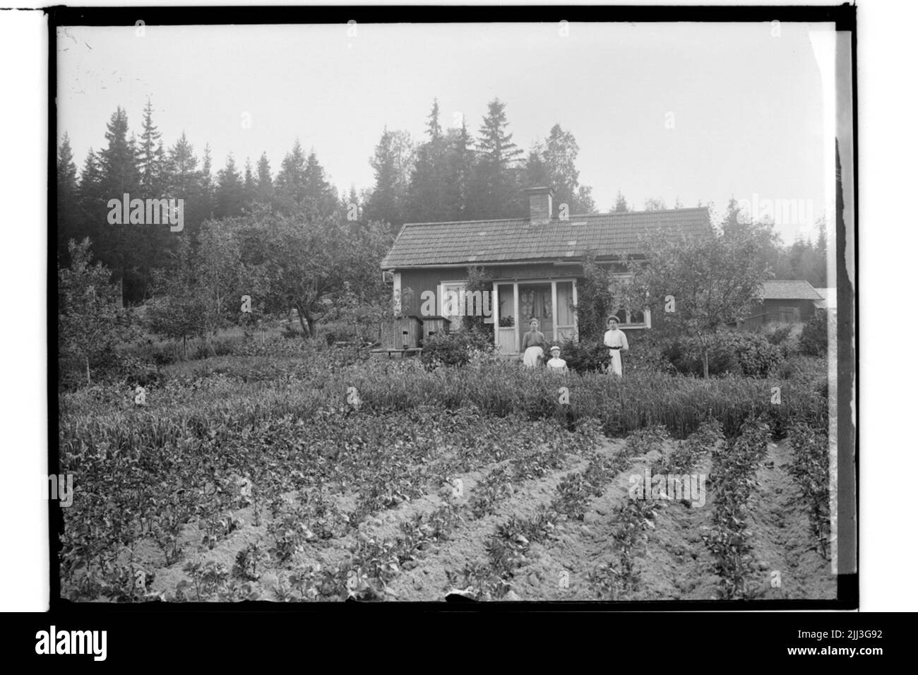 One -story couple's cottage, 3 people in front of the cottage, 2 hives ...