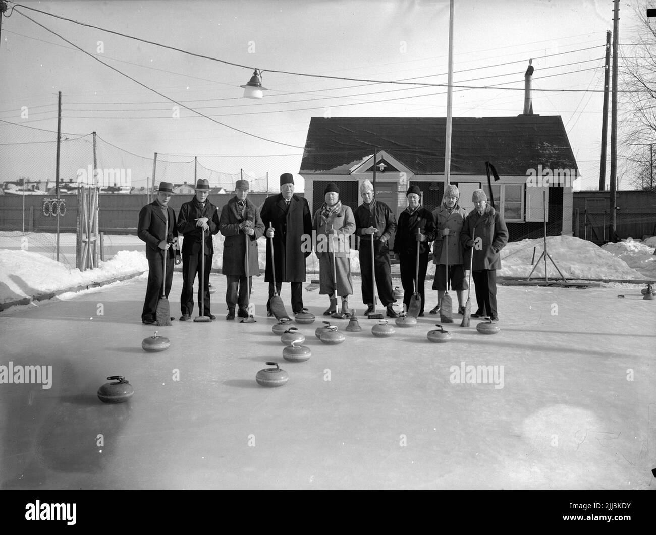 Nine curling players, in the background the clubhouse is visible. From ...