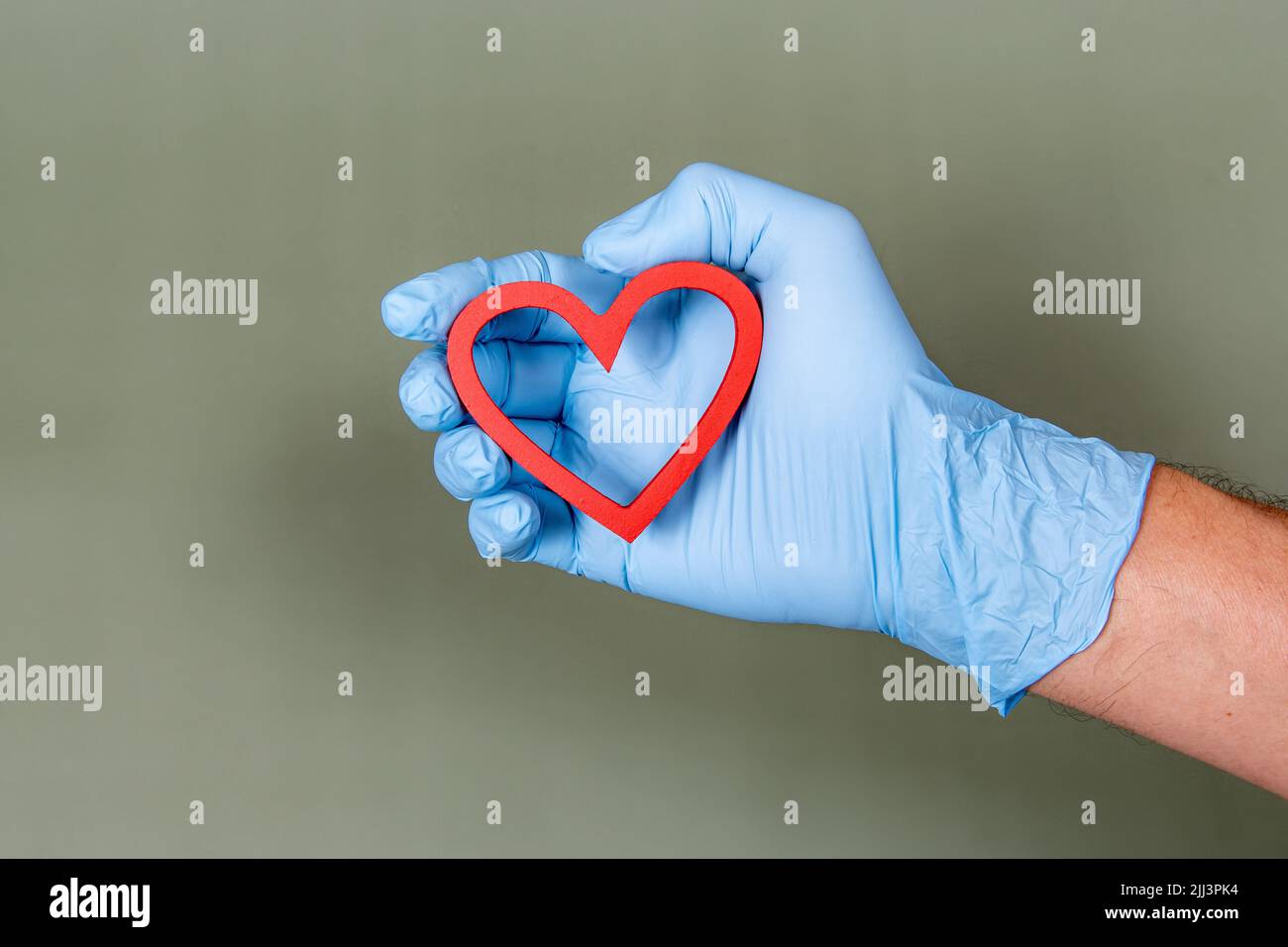 Cirurgical gloved hand holding a heart shape Stock Photo - Alamy