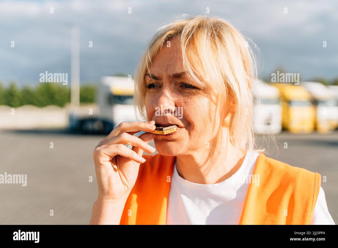 Middle aged portrait of worker engineer woman with orange vest eating ...