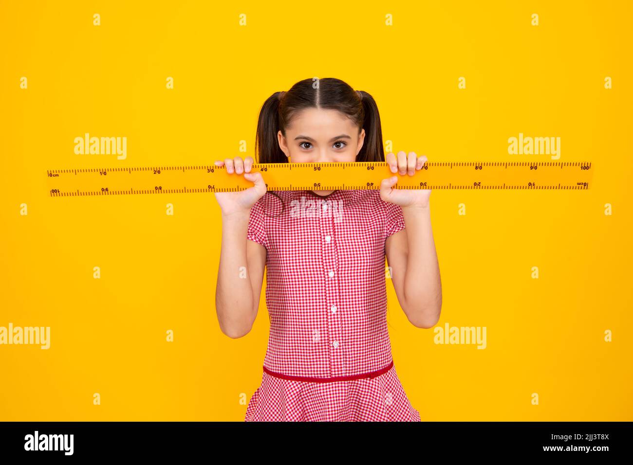 Back to school. School girl hold ruler measuring isolated on yellow ...