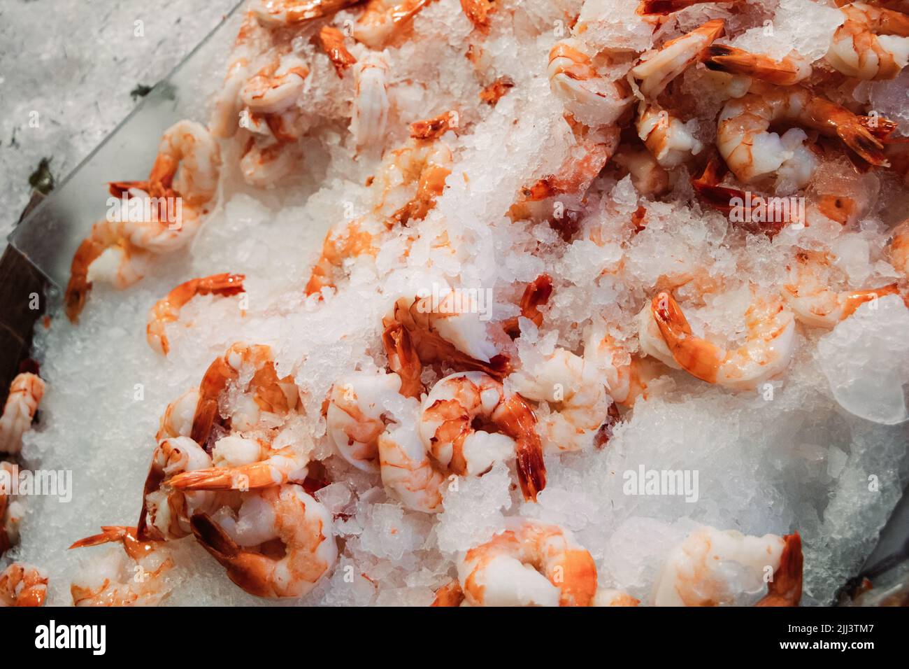 A pile of large pink shrimp sitting on ice at an outdoor farmer's ...