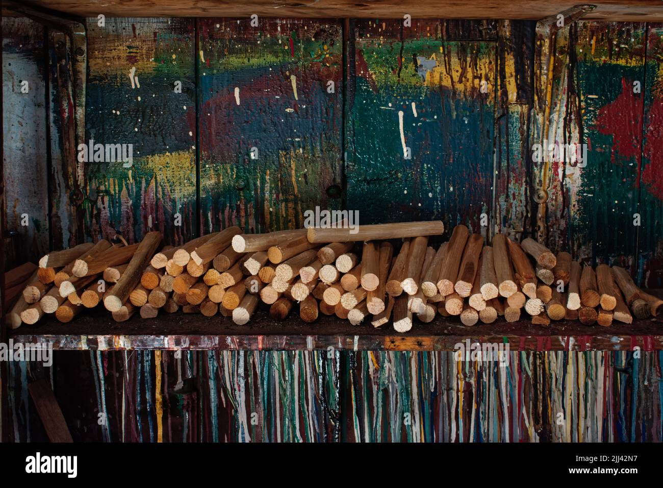 Wooden bung plugs stacked on shelf against a colorful paint spattered ...