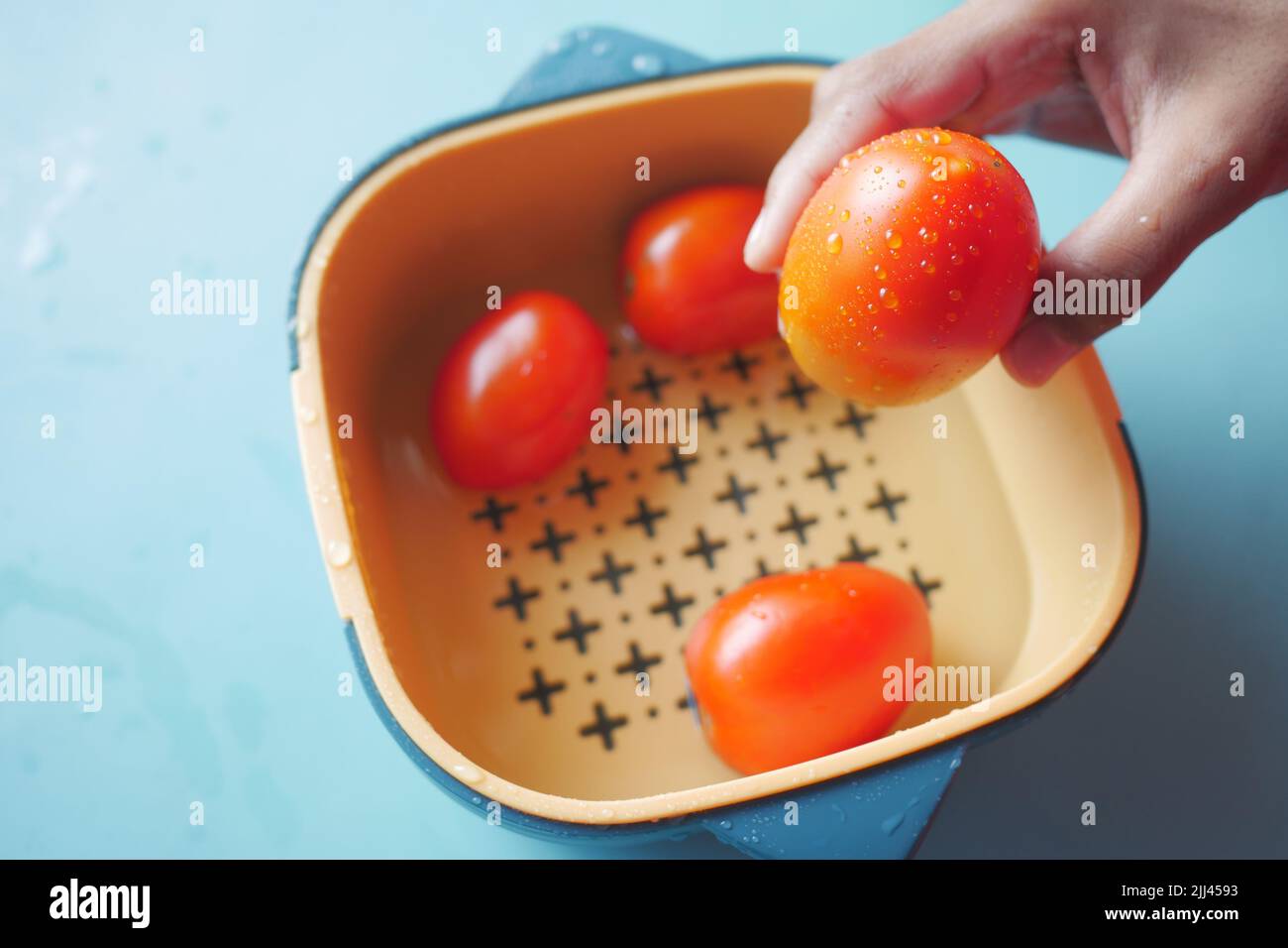 cleaning fresh tomato with a water in a plastic bowl Stock Photo - Alamy
