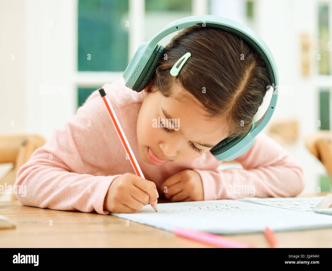 Music and homework. an adorable little girl listening to music while ...