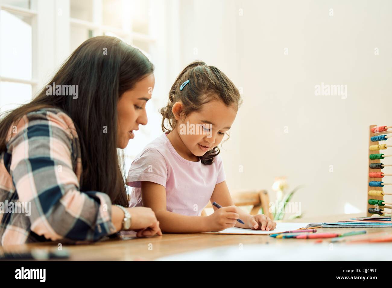 Shes both mother and teacher. an adorable little girl doing her ...