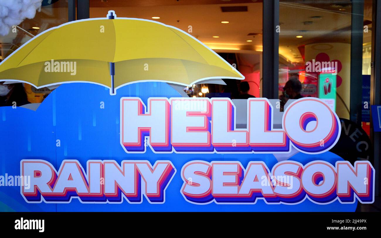 'Hello Rainy Season' sign includes a yellow umbrella and advertises a ...