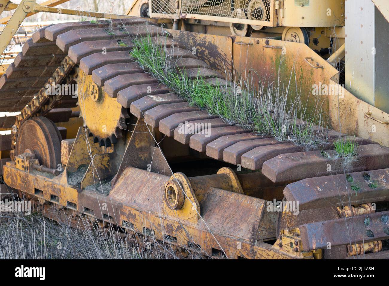 old rusted abandoned tractor track with grass Stock Photo - Alamy