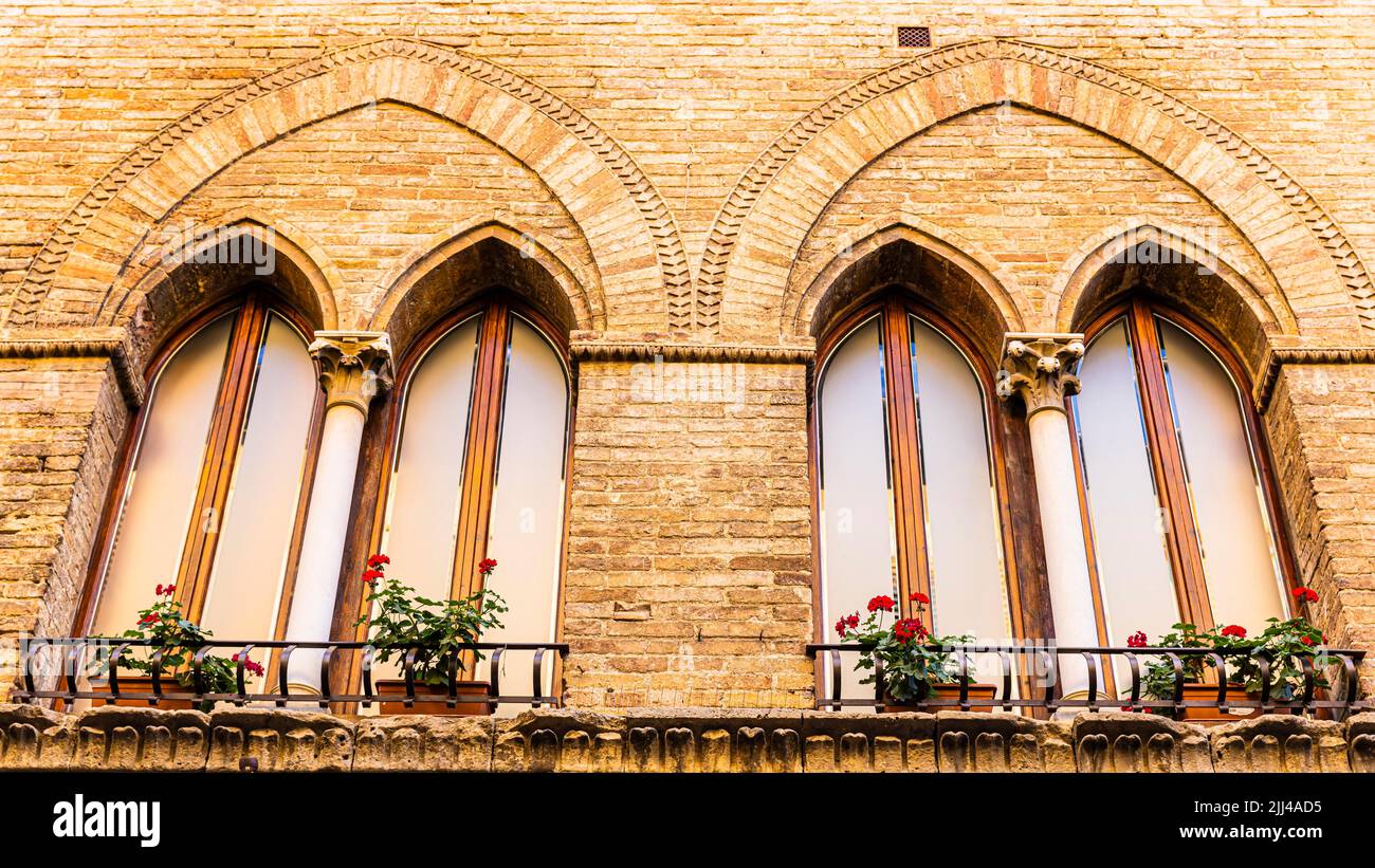 Gothic windows decorated with flower boxes, San Gimignano, Tuscany ...