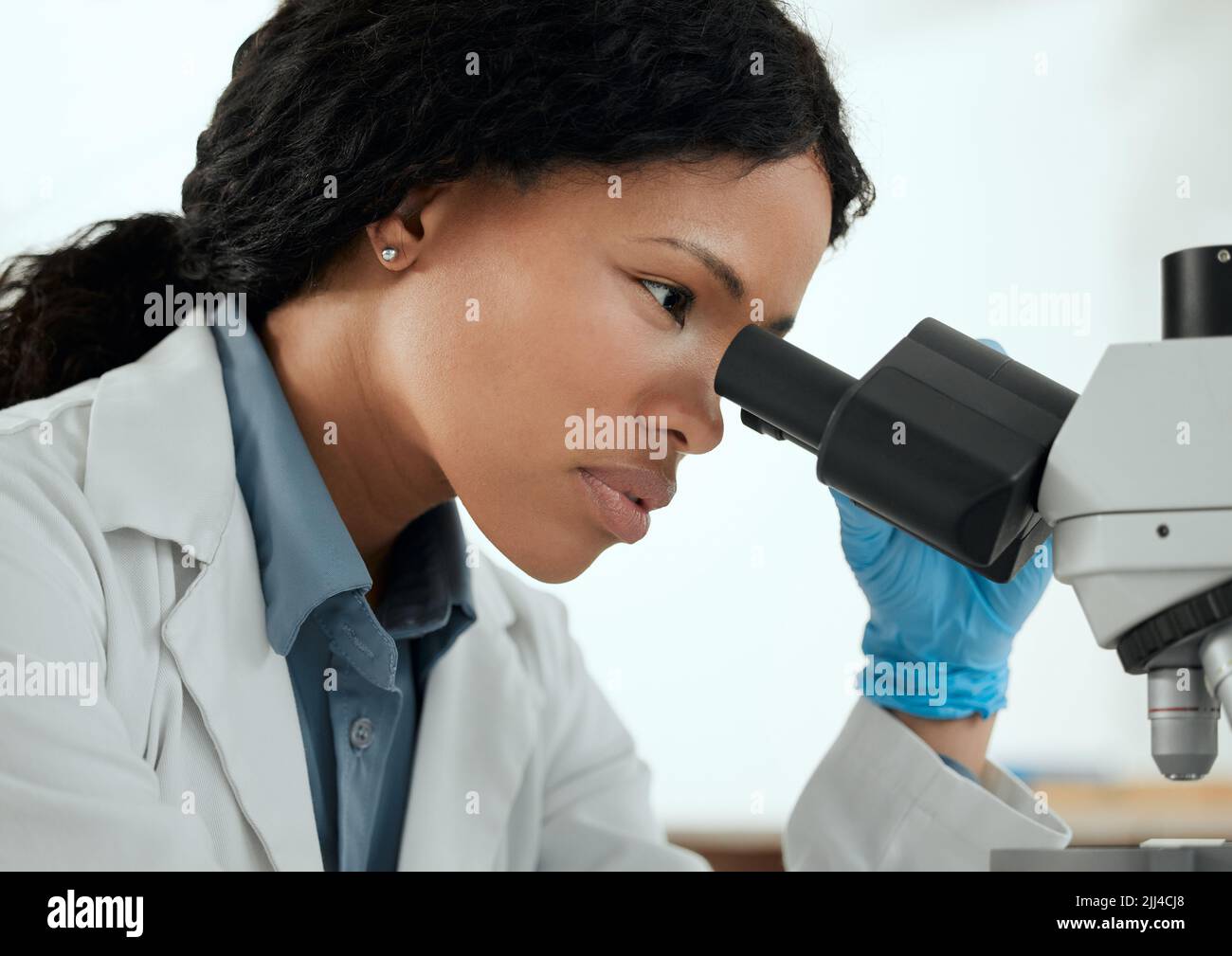 Shes ready to do the work. a young woman using a microscope in a ...
