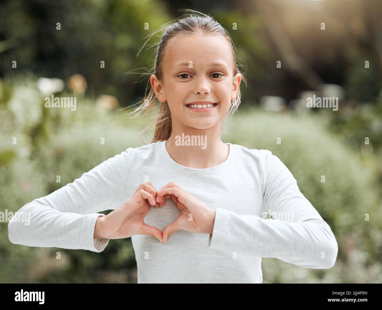 Raised with love. an adorable little girl showing the heart symbol ...