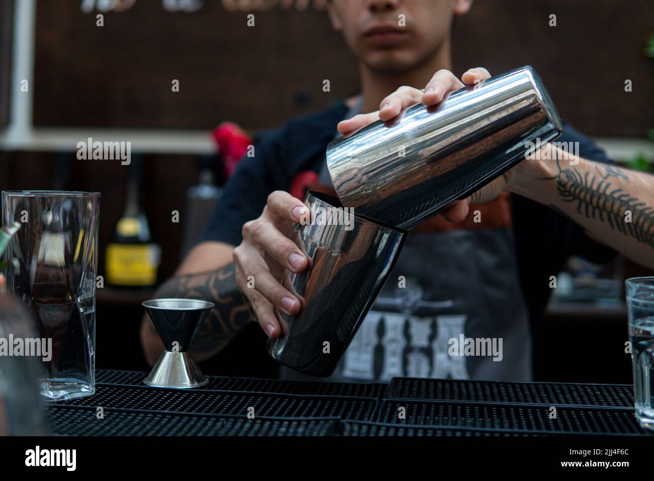 Waiter working at the bar mixing a drink to serve it in a glass. Latino ...