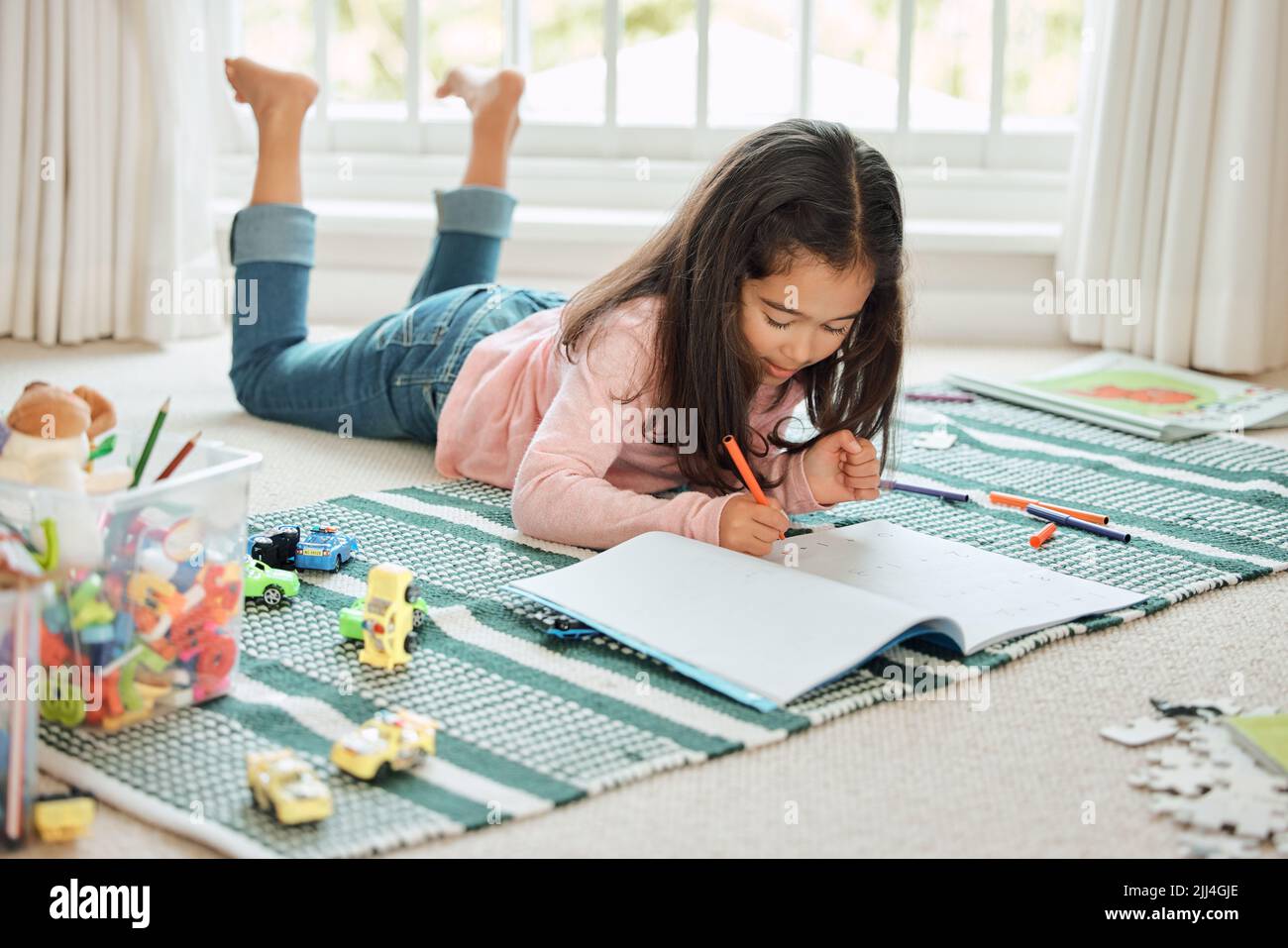 Its almost playtime. a little girl doing homework at home Stock Photo ...