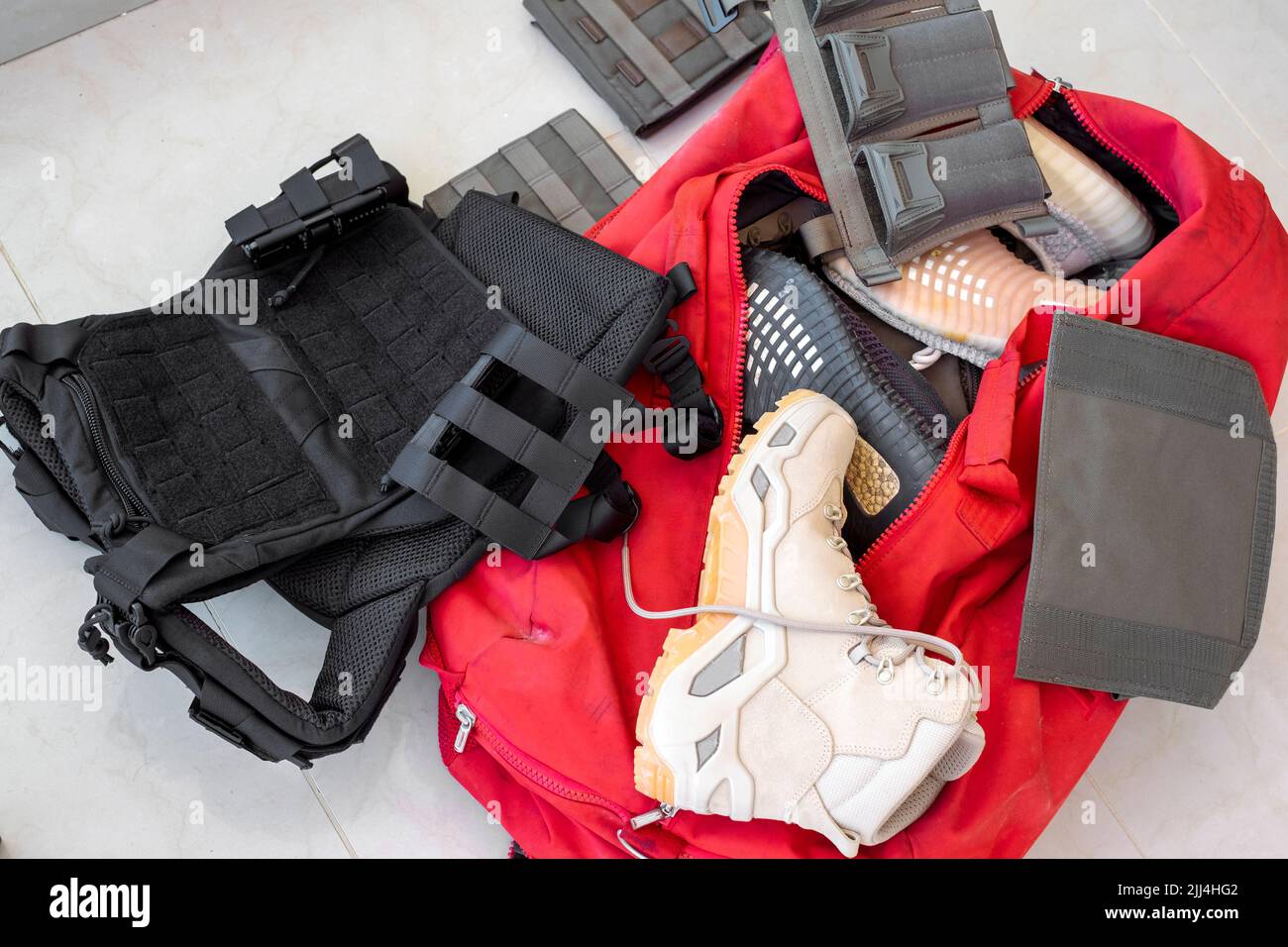 tactical boots, magazine holders and bulletproof vest in red travel bag ...
