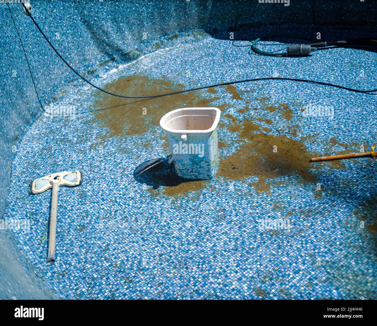 a bucket and brush inside an empty above ground pool, summertime shot ...