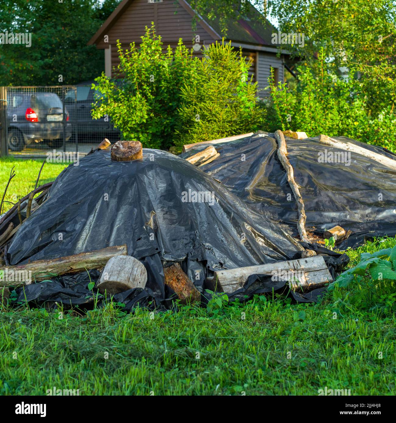 suburban landscape with two heaps of trash covered with plastic foil ...