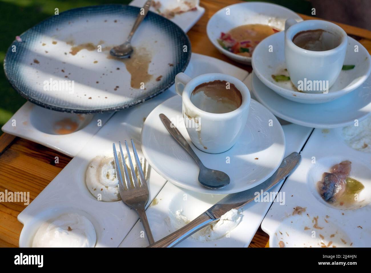 finished dinner and dirty dishes on a messy table, outdoor closeup ...