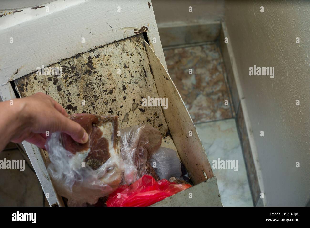a hand throwing spoiled meat into a garbage, selective focus closeup ...